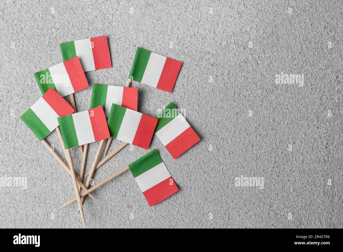 Small paper flags of Italy on grey textured table, flat lay. Space for ...