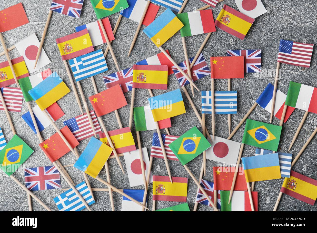 Many small paper flags of different countries on grey table, flat lay ...