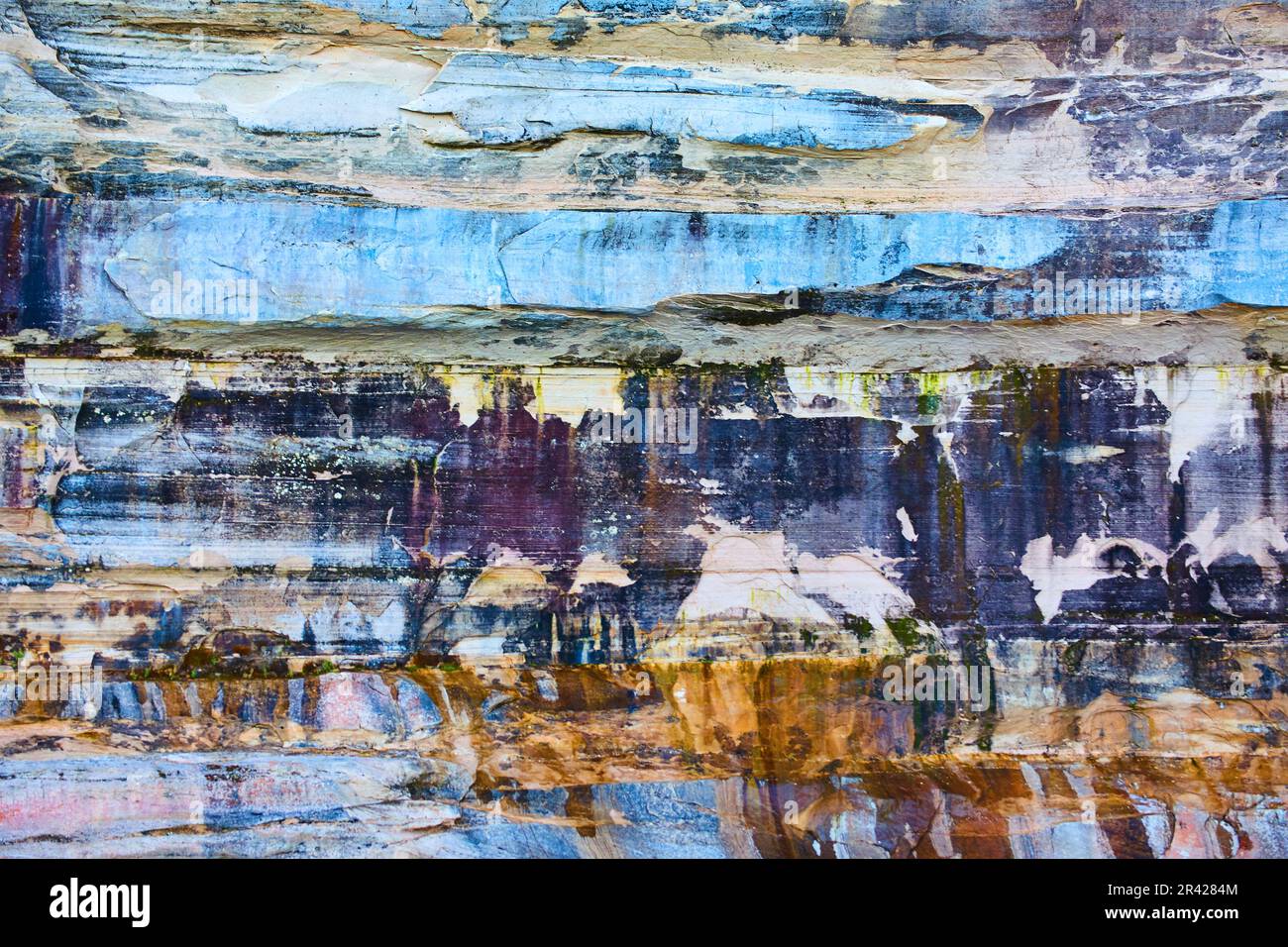 Cliff wall background with blue, black, and rust colored stone at ...