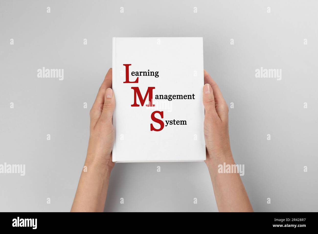 Woman holding book with text Learning Management System and red initial ...