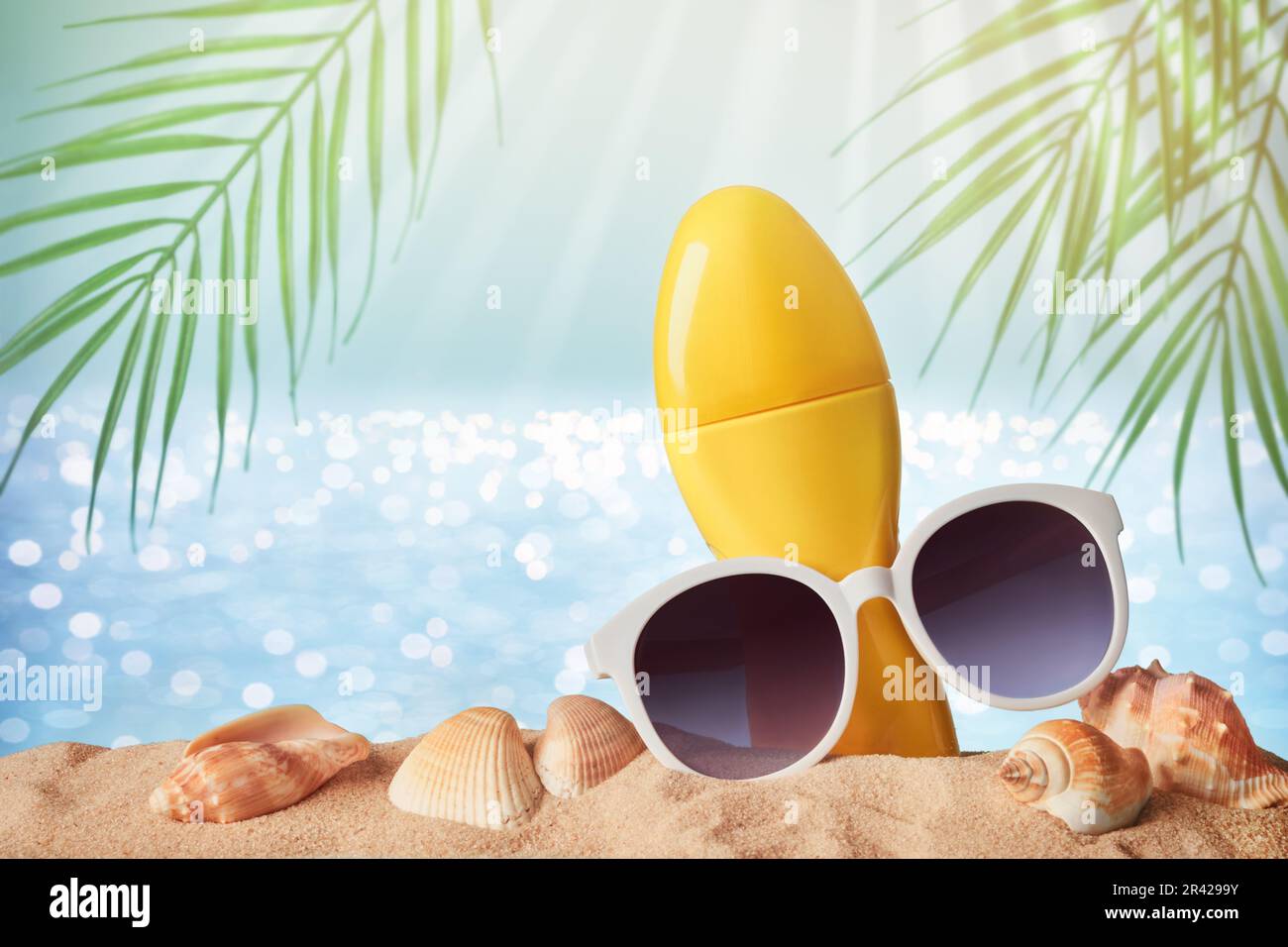 Yellow tube sunscreen and sunglasses on blurred sea background with ...