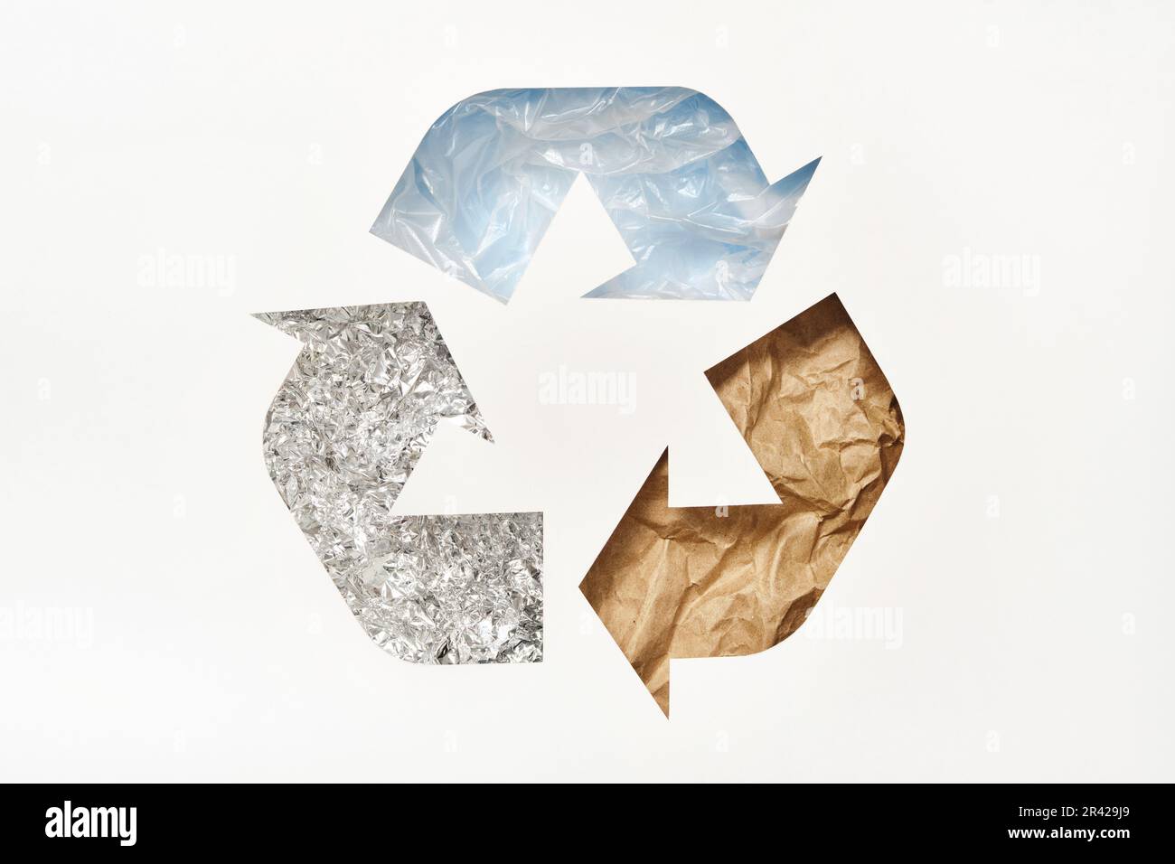 Recycle symbol made of cut paper with plastic, paper and foil on blue ...
