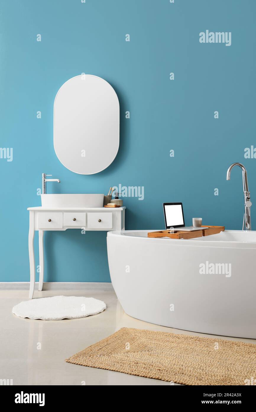 Interior of bathroom with bathtub, modern laptop and mirror Stock Photo ...