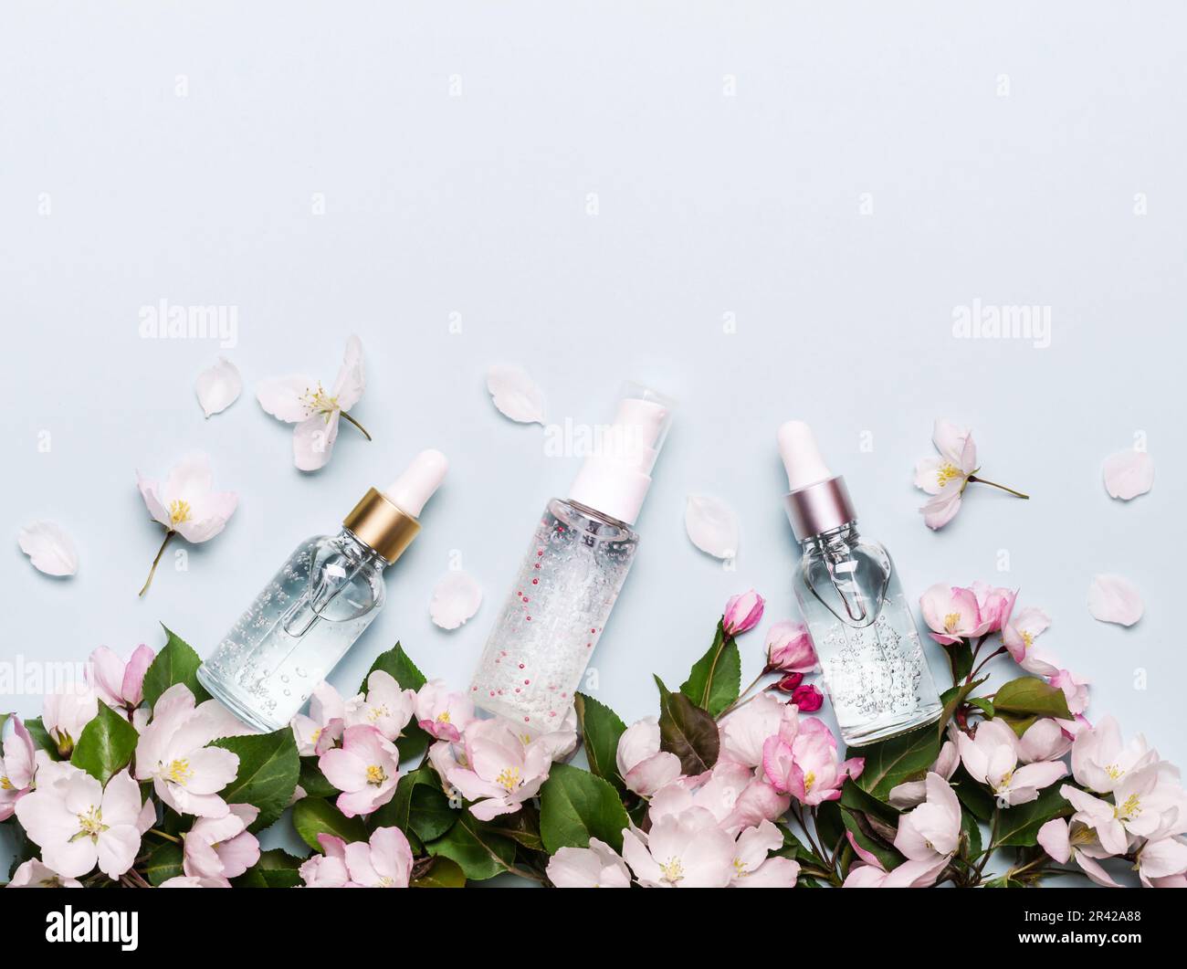 Set of cosmetic liquid gel products and flowering apple twig border on ...