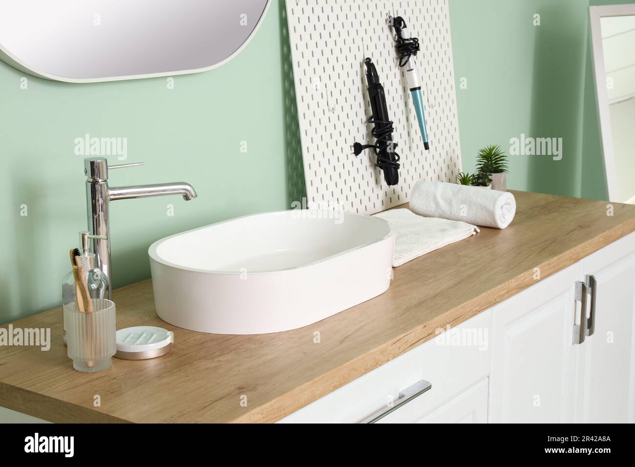 Counter with sink bowl, tooth brushes and hair styling tools on ...