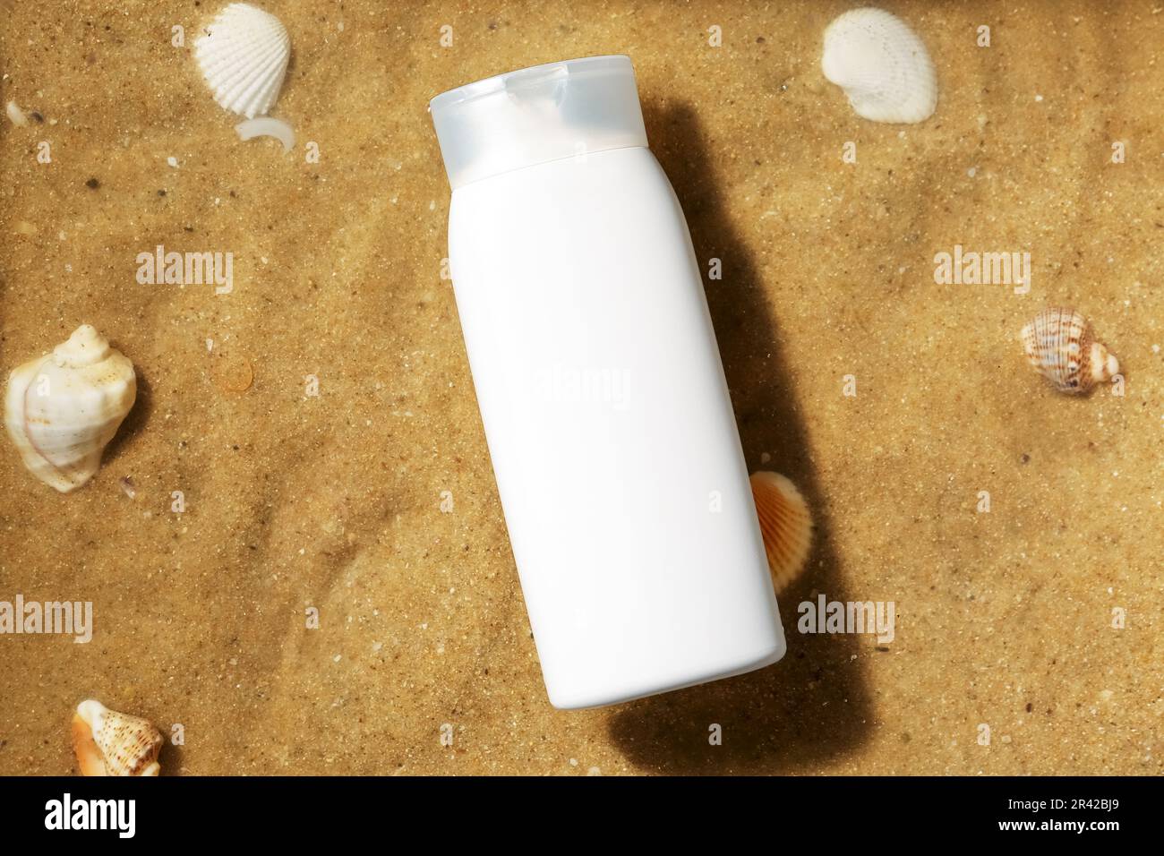 Bottle of sunscreen cream with seashells in water on sand Stock Photo ...