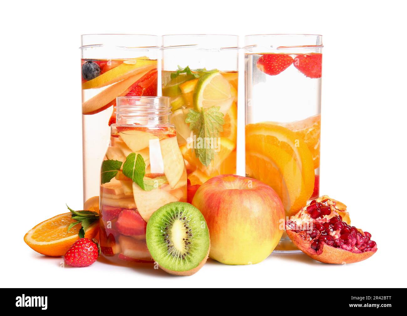 Bottles of infused water with different sliced fruits on white ...