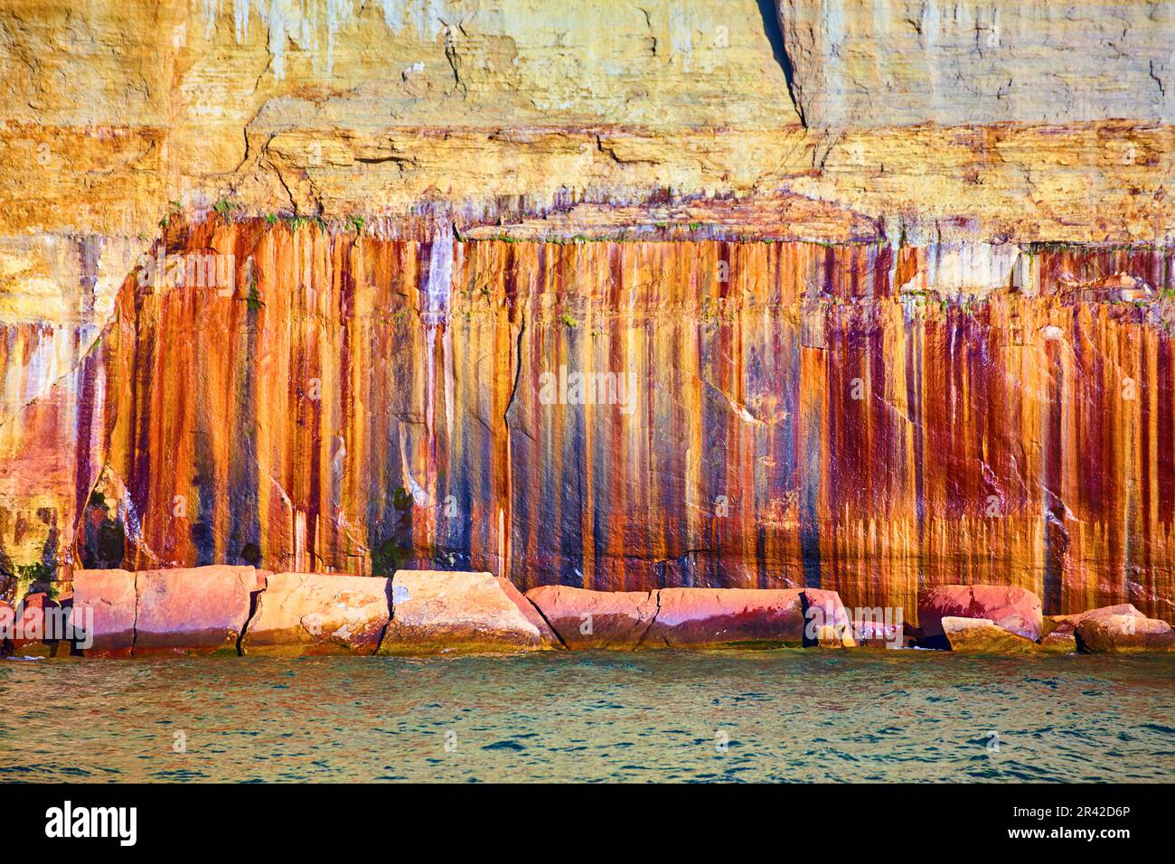 Boulders sticking out of waters near Pictured Rocks cliff face with ...