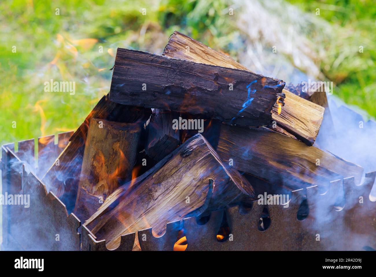 Small folding portable brazier filled with burning wood is placed in ...