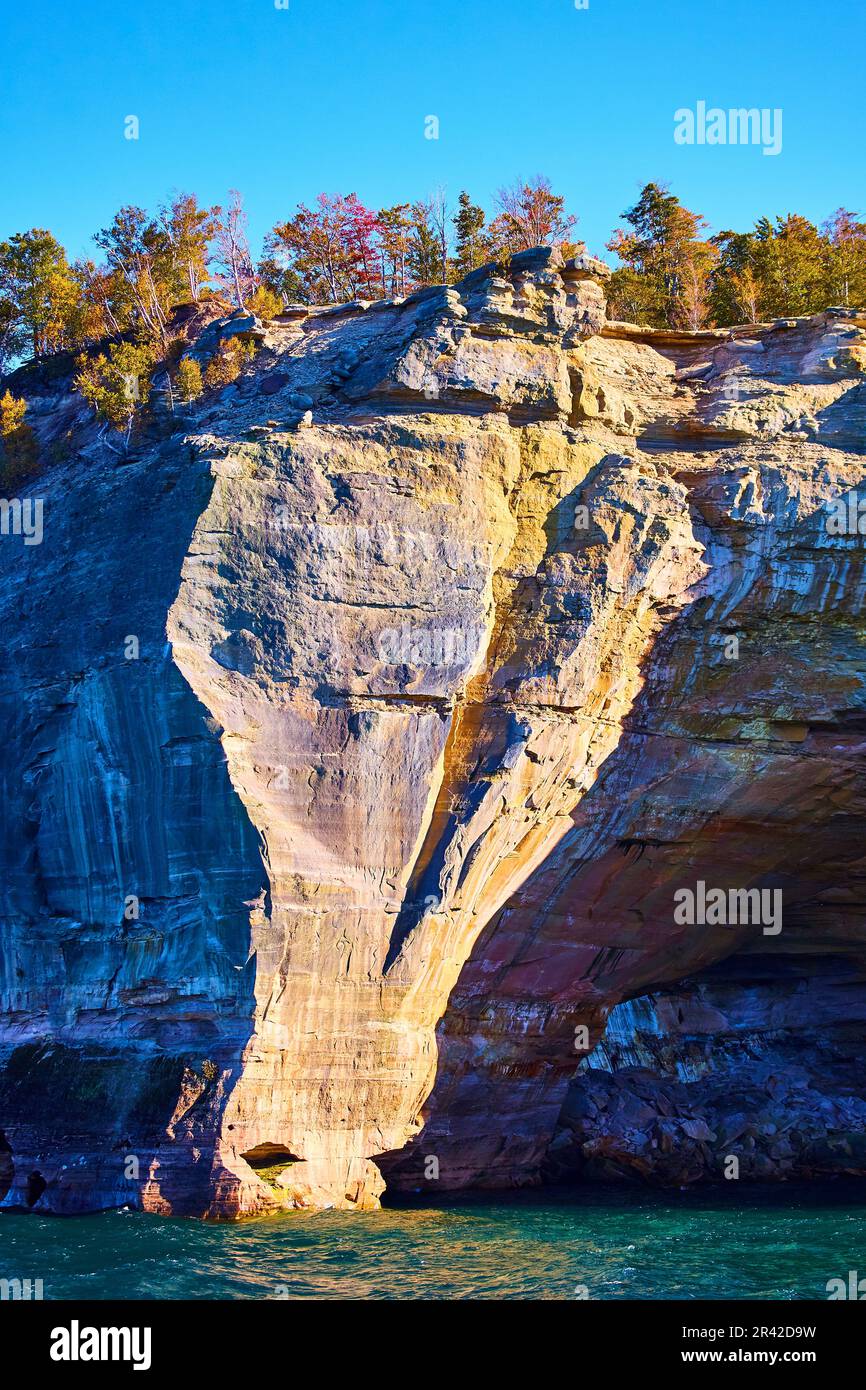 Sun light glinting off stone cliff wall of Pictured Rocks and turquoise ...