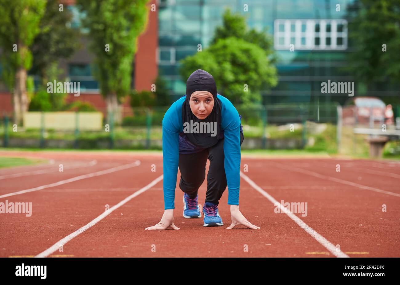 Muslim woman in burqa in sporty Muslim clothes in starting pose for running Stock Photo - Alamy