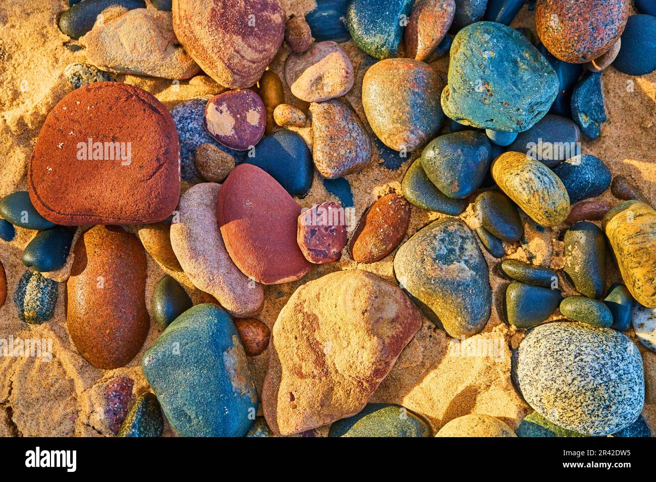 Multiple colors of smooth stones washed up on sandy shore Stock Photo ...