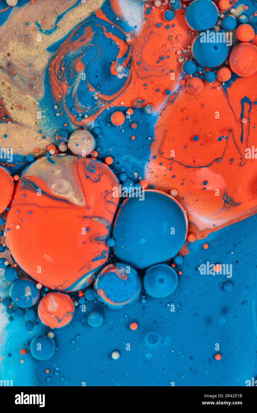 Large circular blobs of blue orange and gold in abstract pour of ...