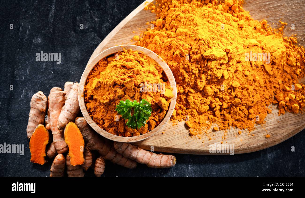 Composition with a bowl of ground turmeric and its fresh rhizome Stock ...