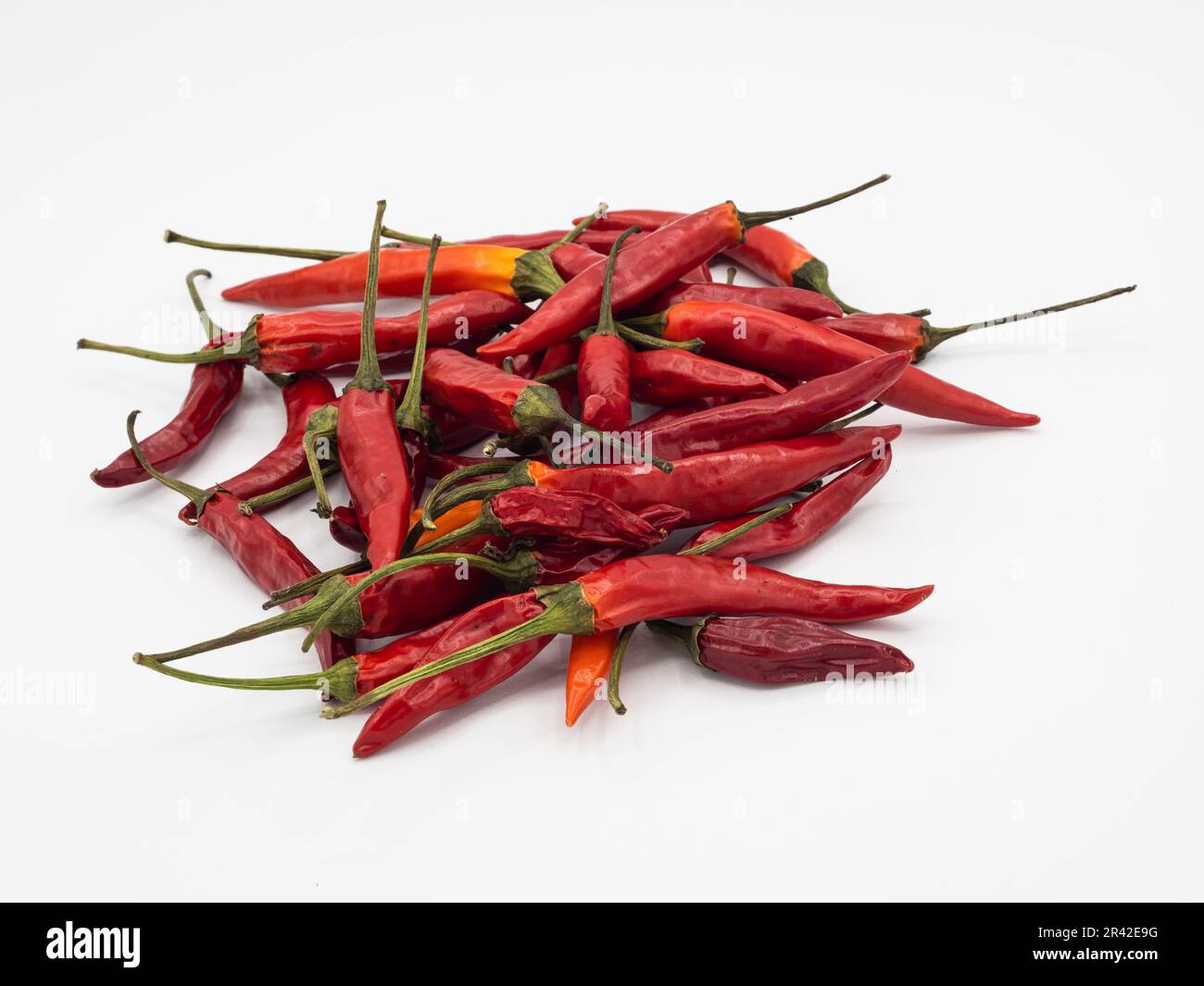 A side view of chili fruits in red and orange colors on a white ...