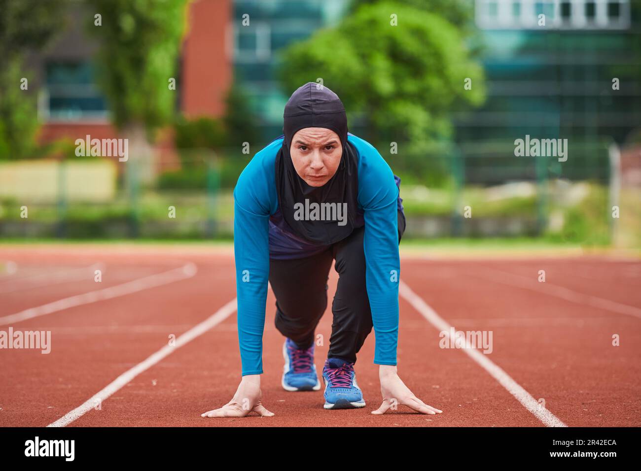 Muslim woman in burqa in sporty Muslim clothes in starting pose for ...