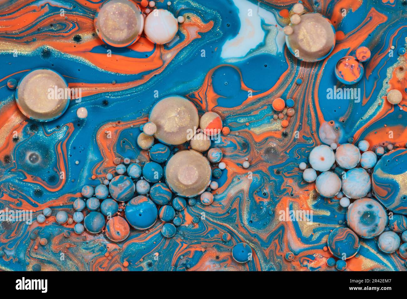 Floating bubbles of swirling blue orange gold and white in sea of oil ...