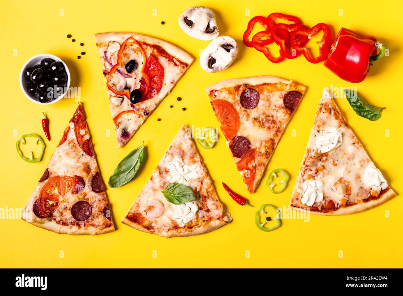 Selection of Assorted pieces pizza on yellow background and ingredients ...