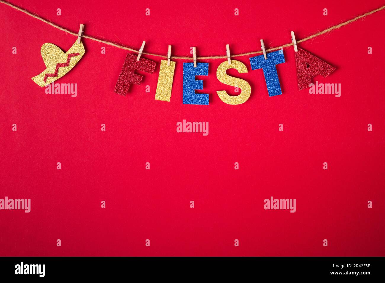 Fiesta word and sombrero on pins made of shiny paper on red background ...