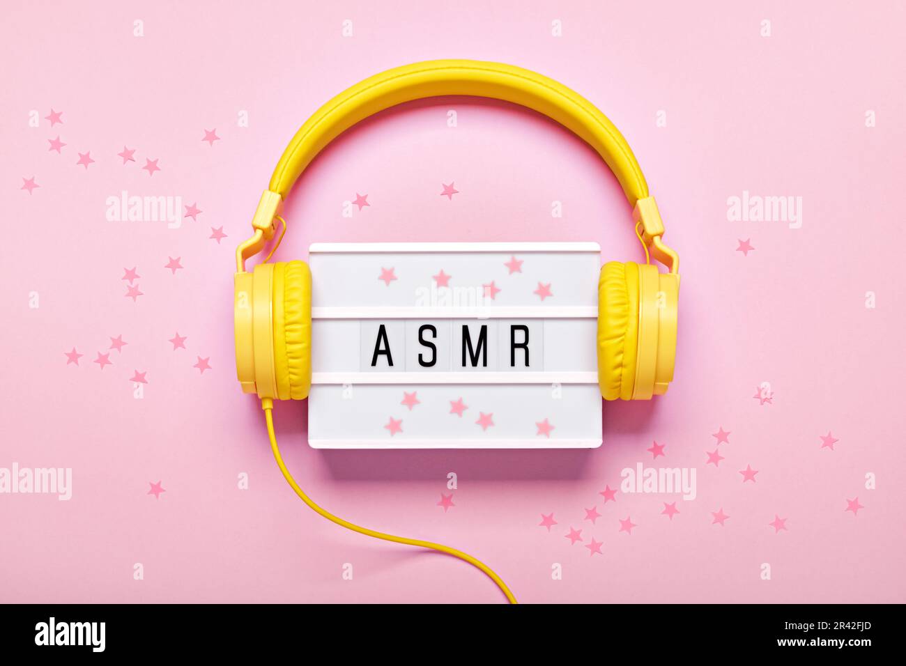 Yellow headphones, ASMR letters lightbox and confetti on pink ...
