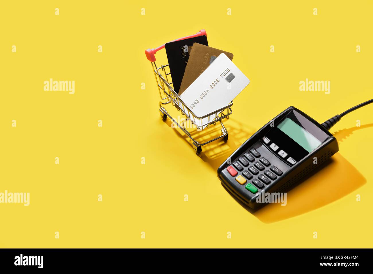 POS payment terminal and shopping cart with bank cards on yellow ...