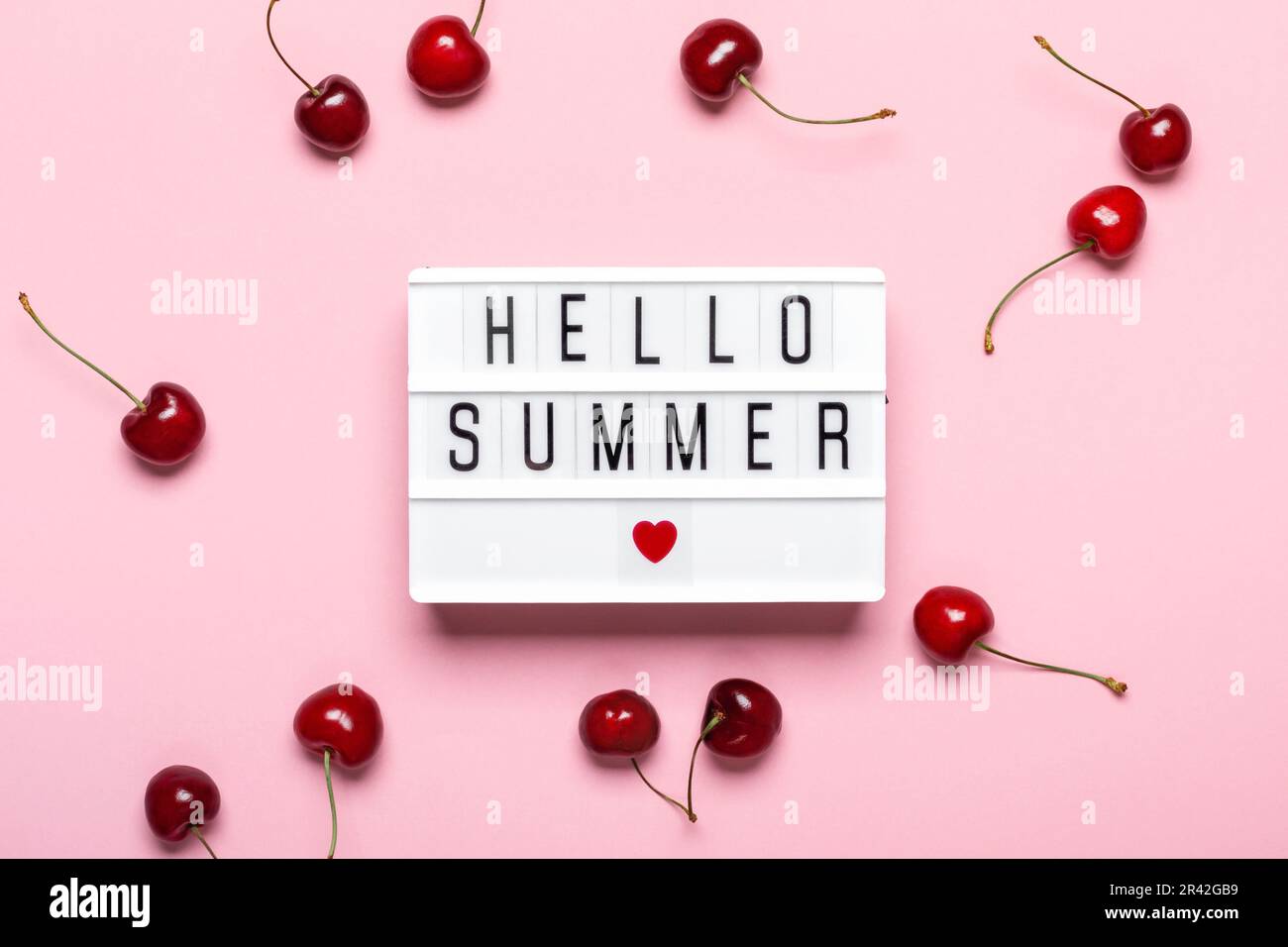 Light box with Hello Summer text and ripe cherries on pink background ...