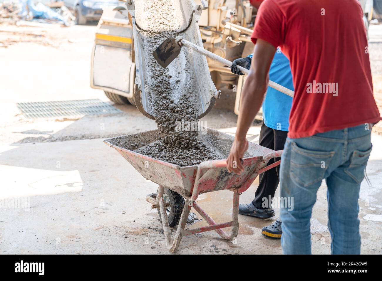 Workers load cement from trucks onto carts to pour the floor in areas ...