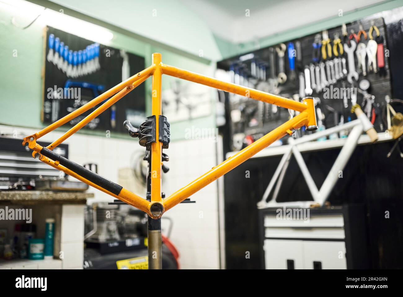 Orange bicycle frame held on a stand in a mechanical bike repair shop ...