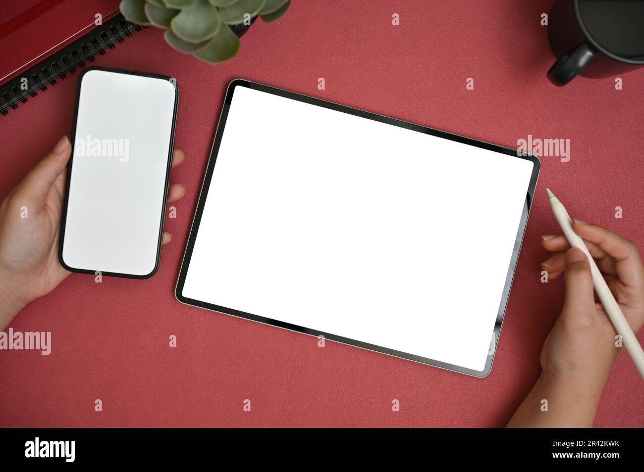 Top view of a female using her smartphone and her digital tablet on a red table. smartphone and ...