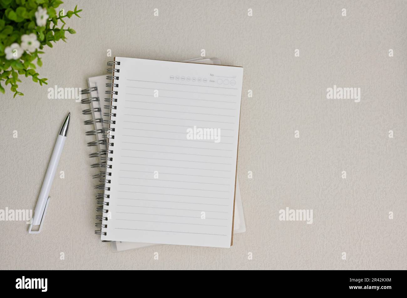 Minimal study table top view with an empty page on a diary, a pen, and ...
