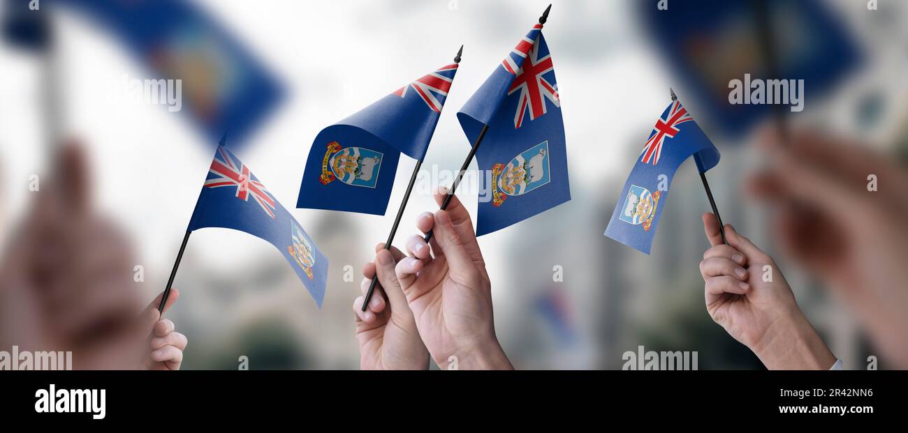 A group of people holding small flags of the Falkland Islands in their ...