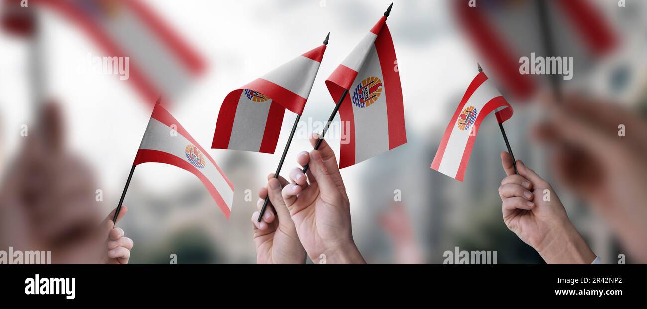 A group of people holding small flags of the French Polynesia in their ...