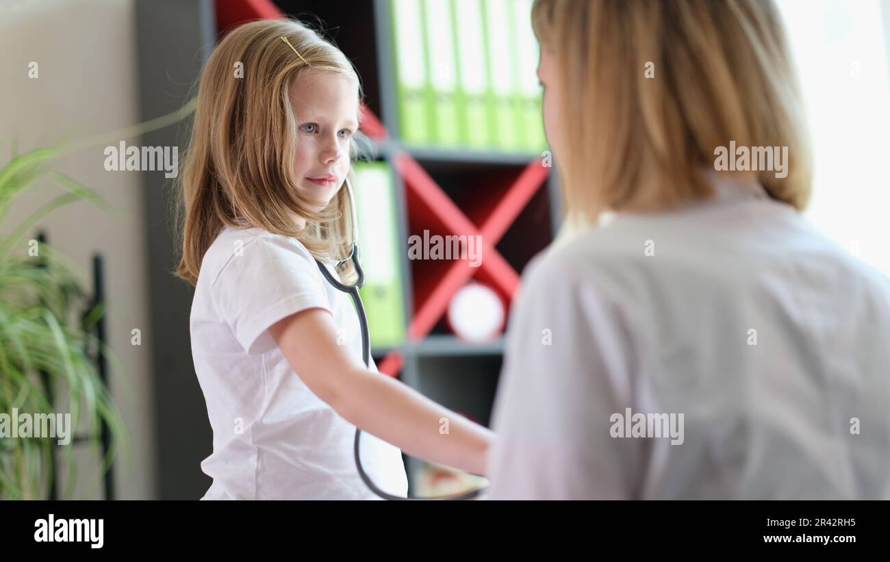 Cute little girl uses stethoscope listening to heart of lady Stock ...