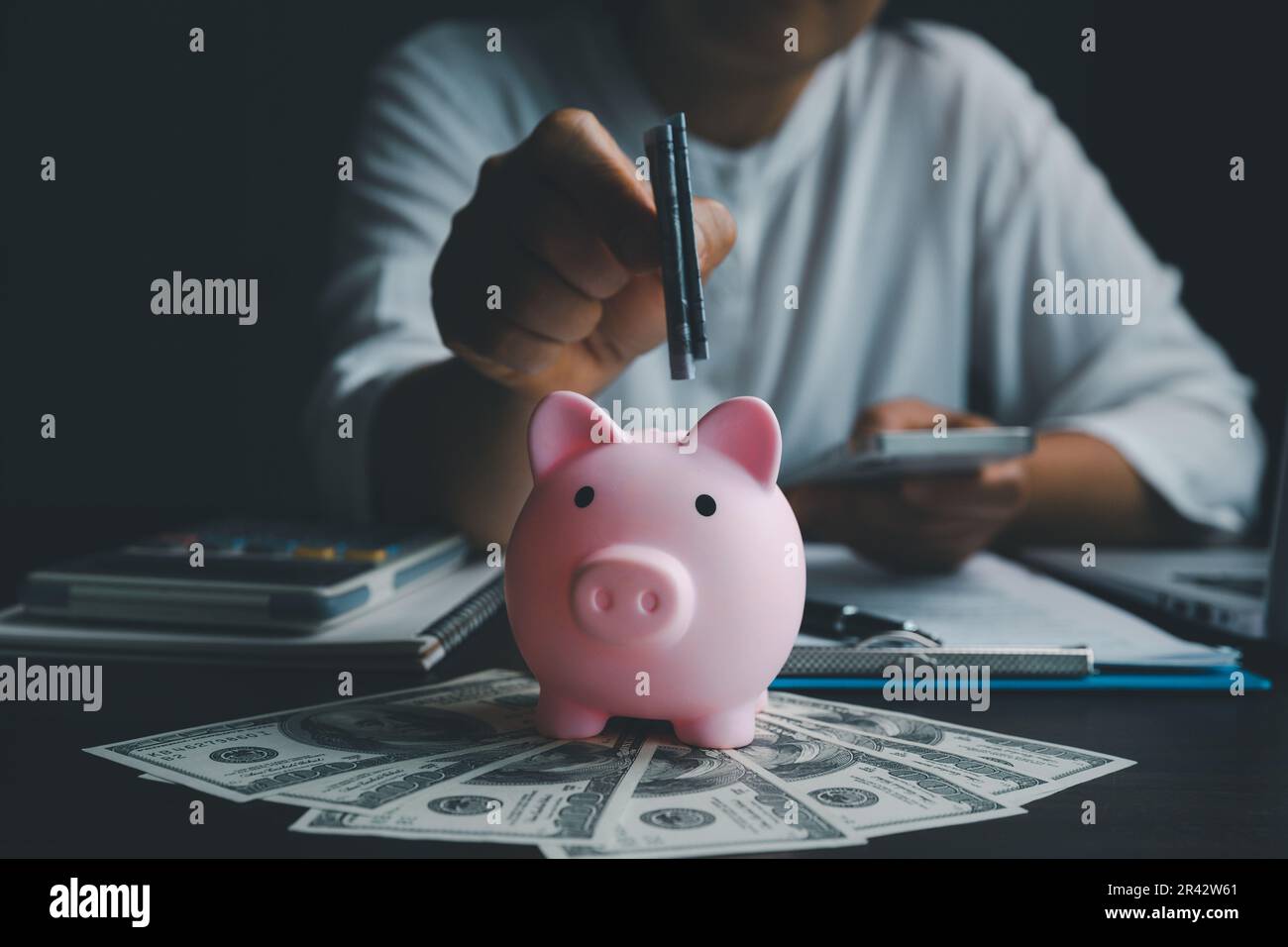 Business woman hand put dollar bill in piggy bank on wood table ...