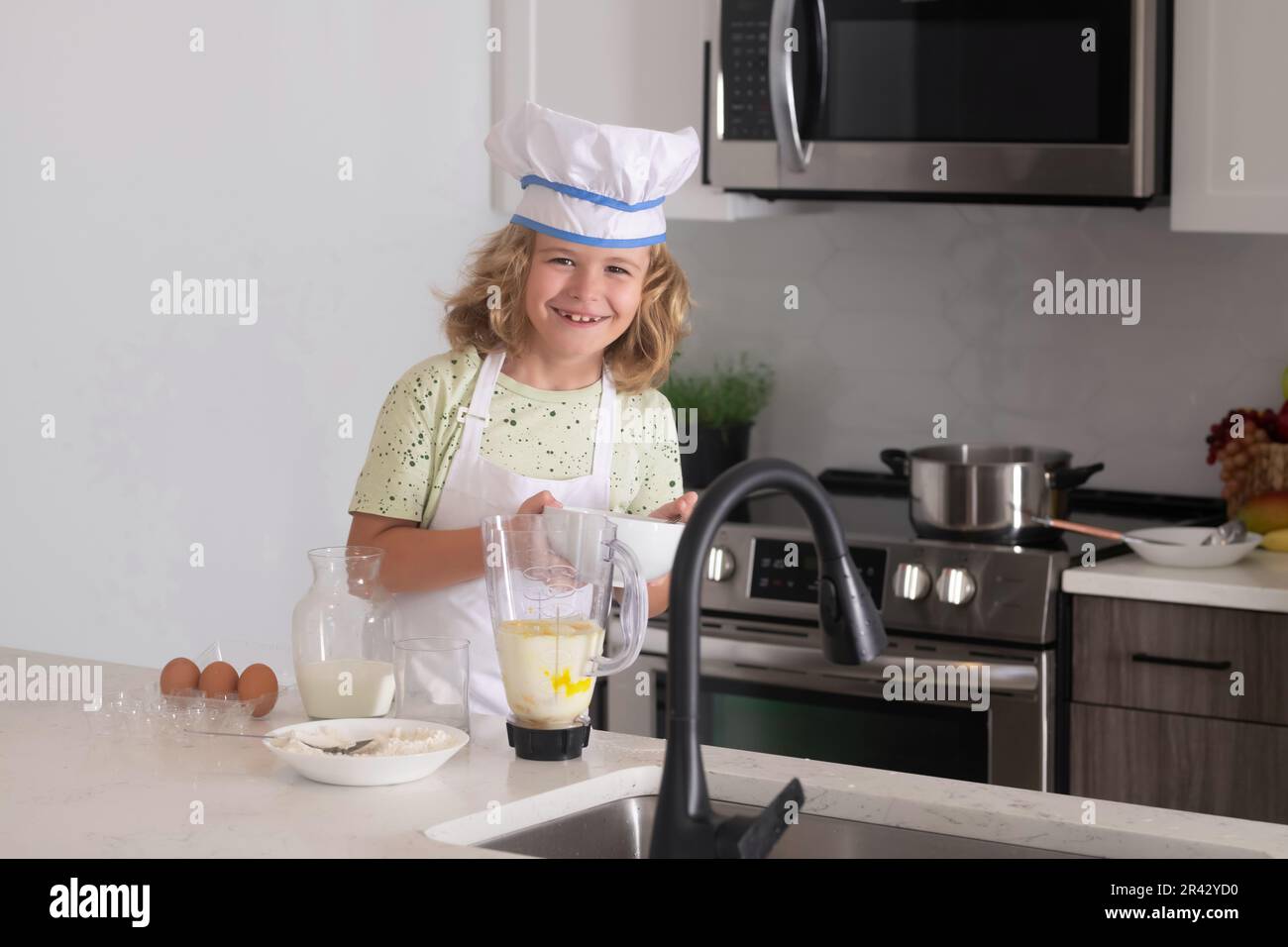 Child chef cook. Funny child stand at kitchen table have fun baking ...