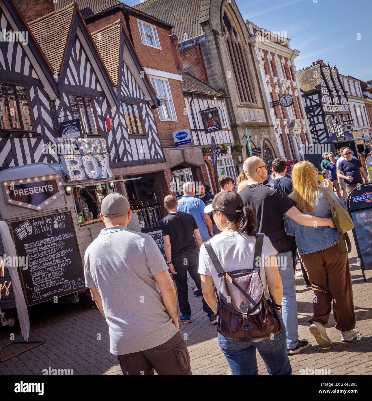 People enjoying the sun while walking along a busy street lined with ...