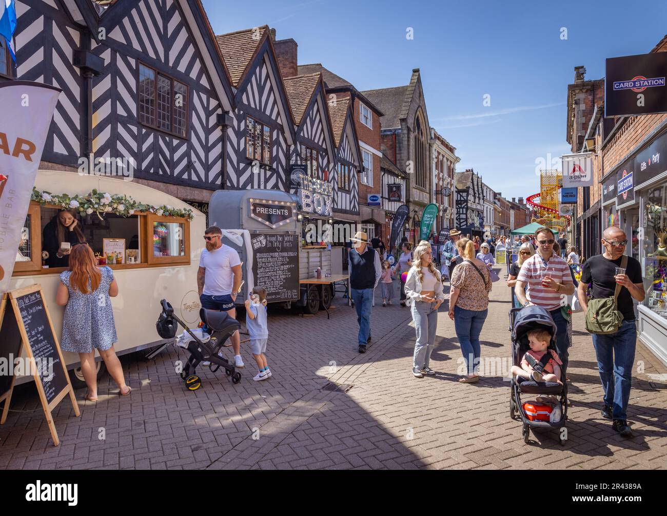 People enjoying the sun while walking along a busy street lined with ...