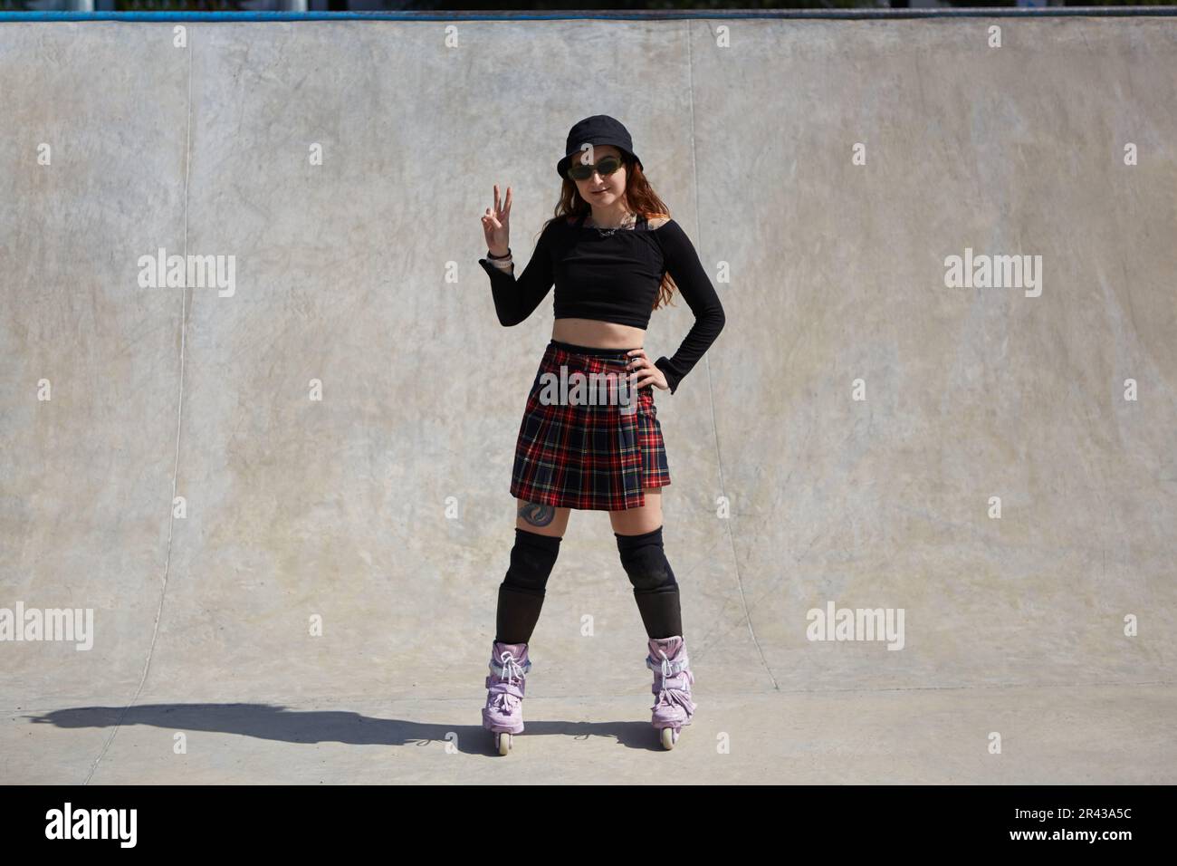 Aggressive inline roller blader female posing in a concrete skate pool ...