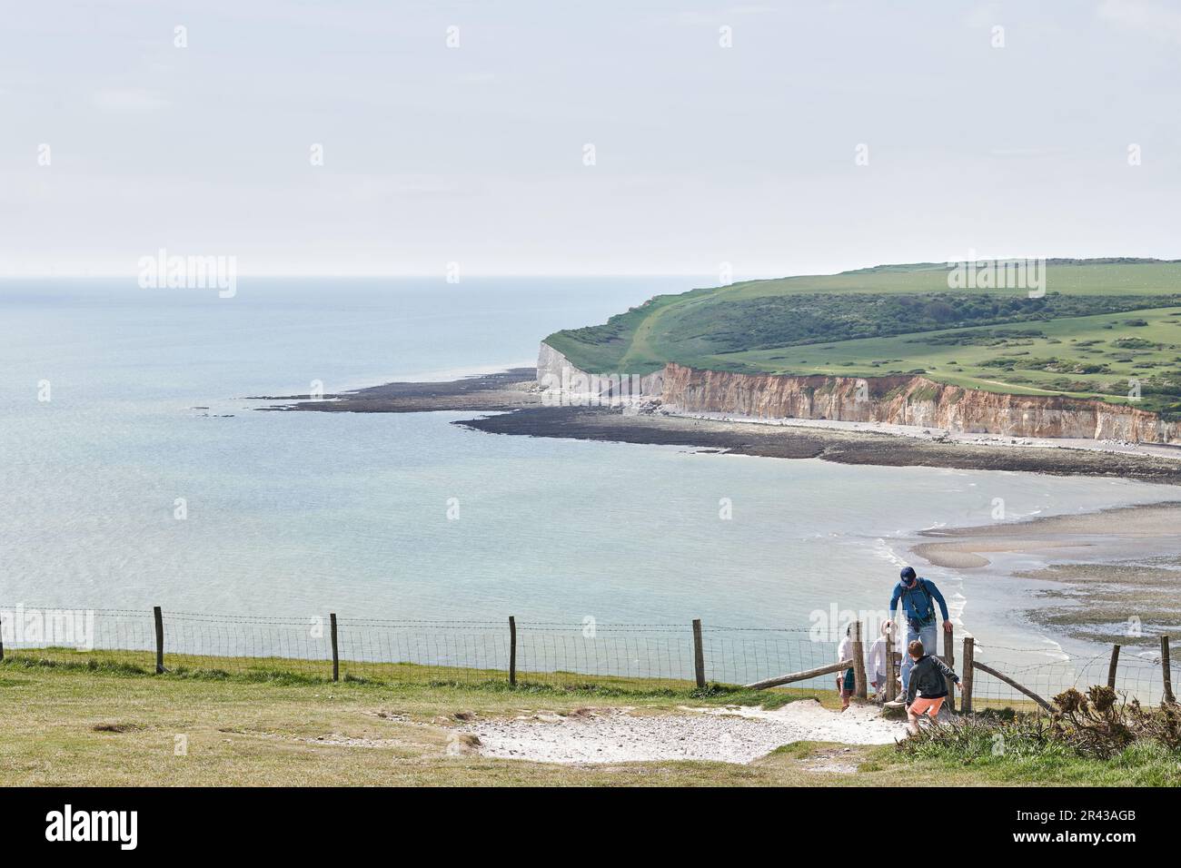 A family climb over a style on the South Downs chalk cliffs at Seven Sisters next Cuckmere Haven ...
