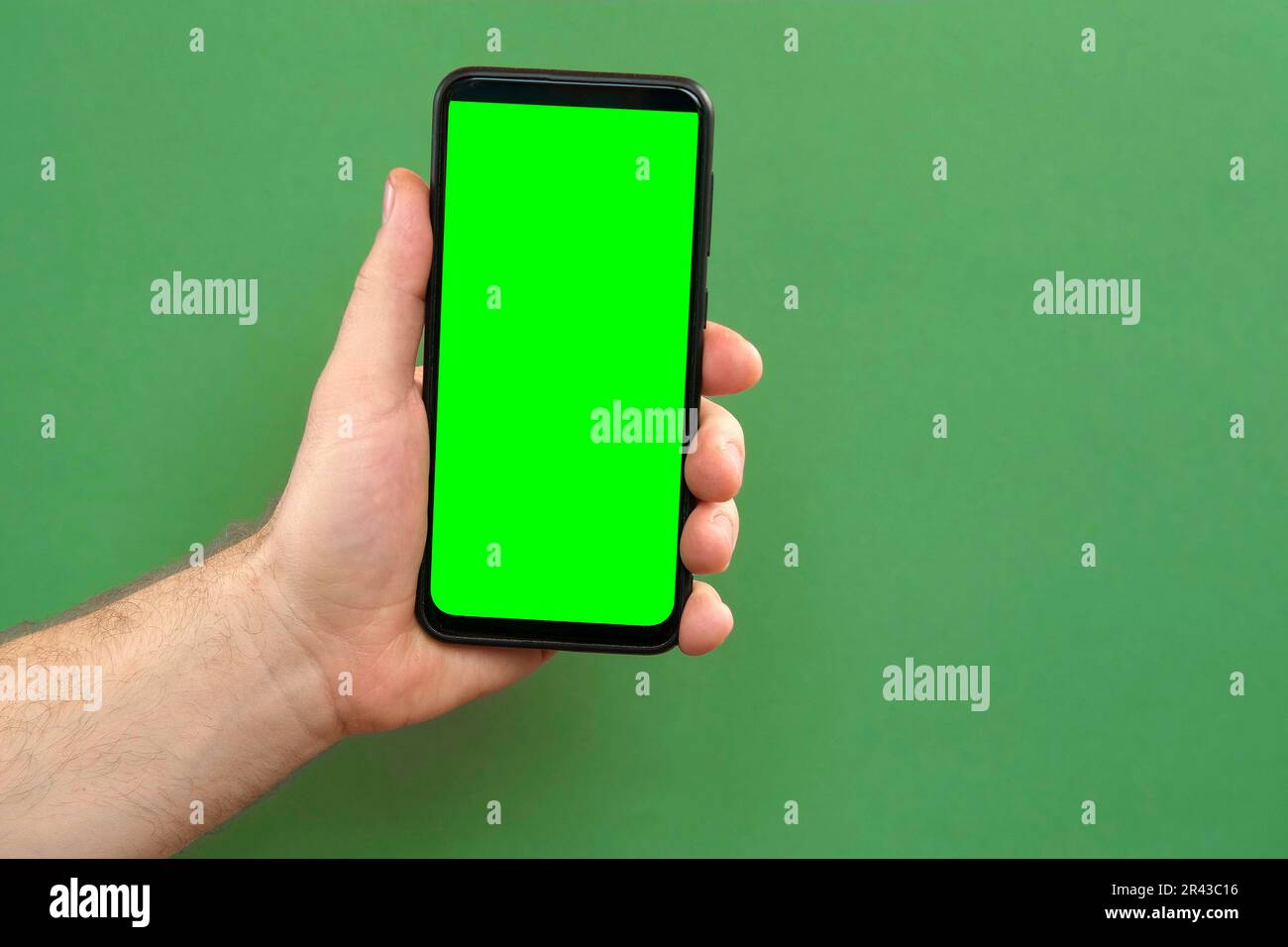 Young man hand use smartphone with green screen on green background ...