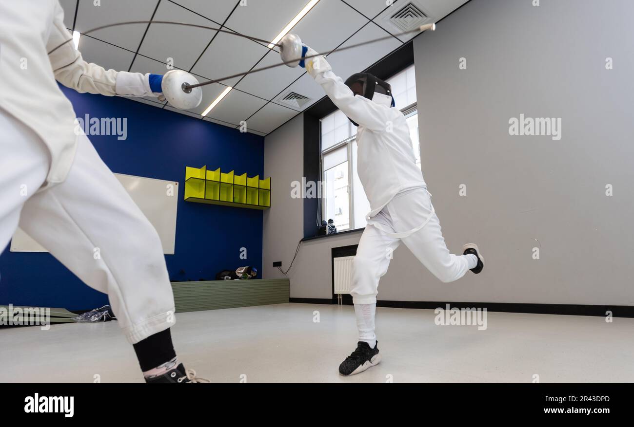 Adults and teens wearing a fencing uniform practicing with foil in the ...