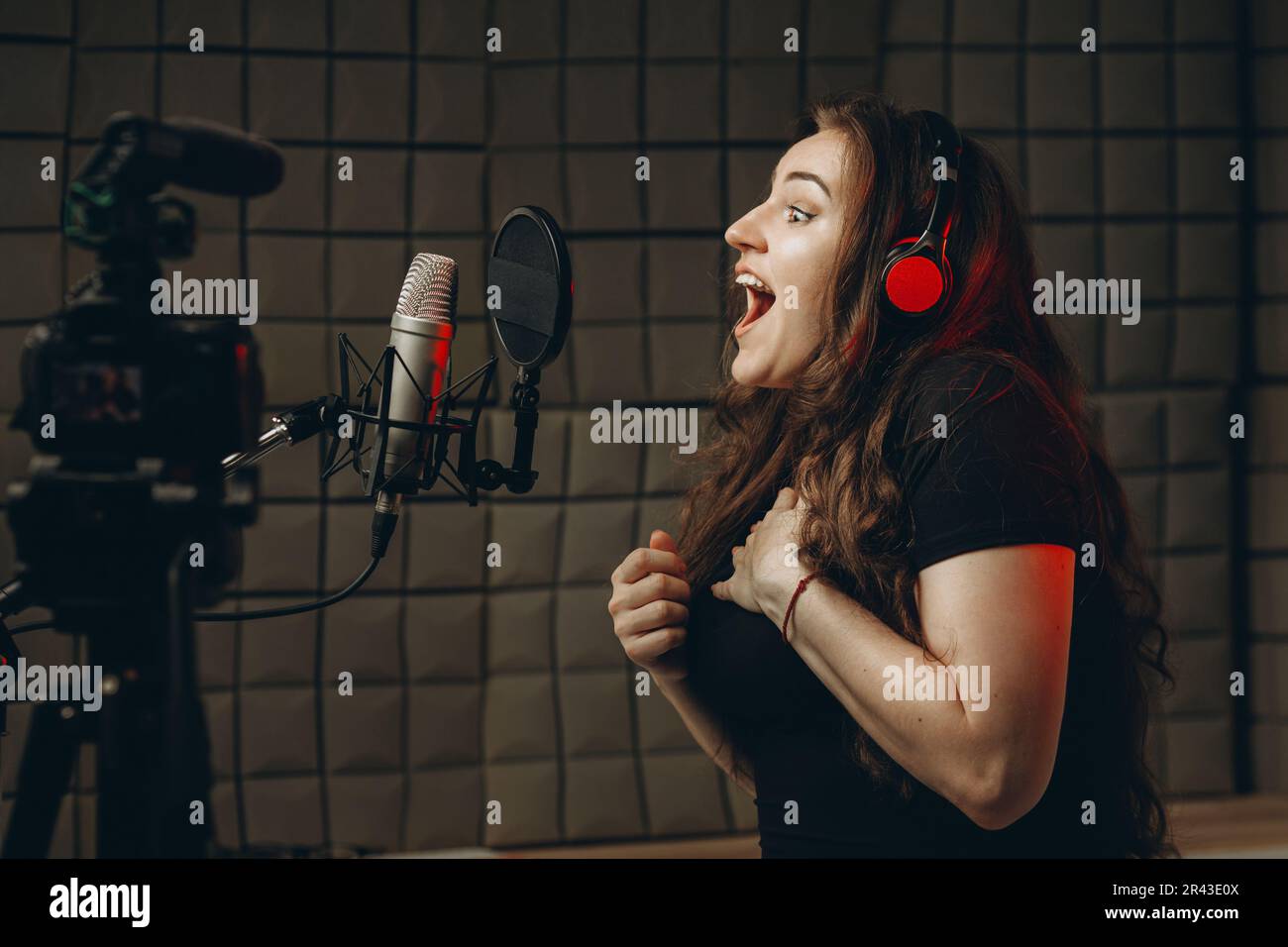 Young girl with microphone and headphones in recording studio ...