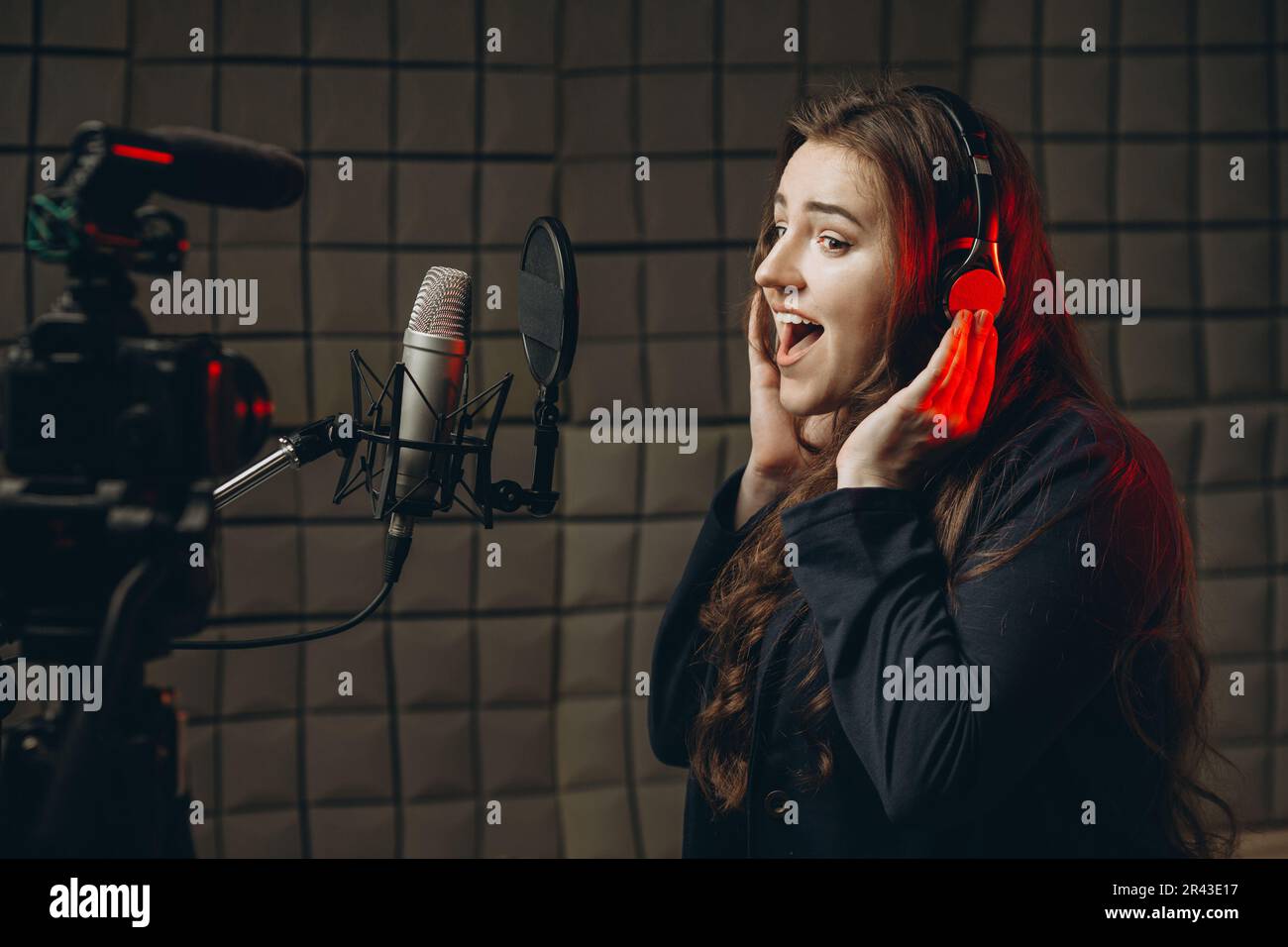 Female with microphone recording a voice for dubbing in music studio ...
