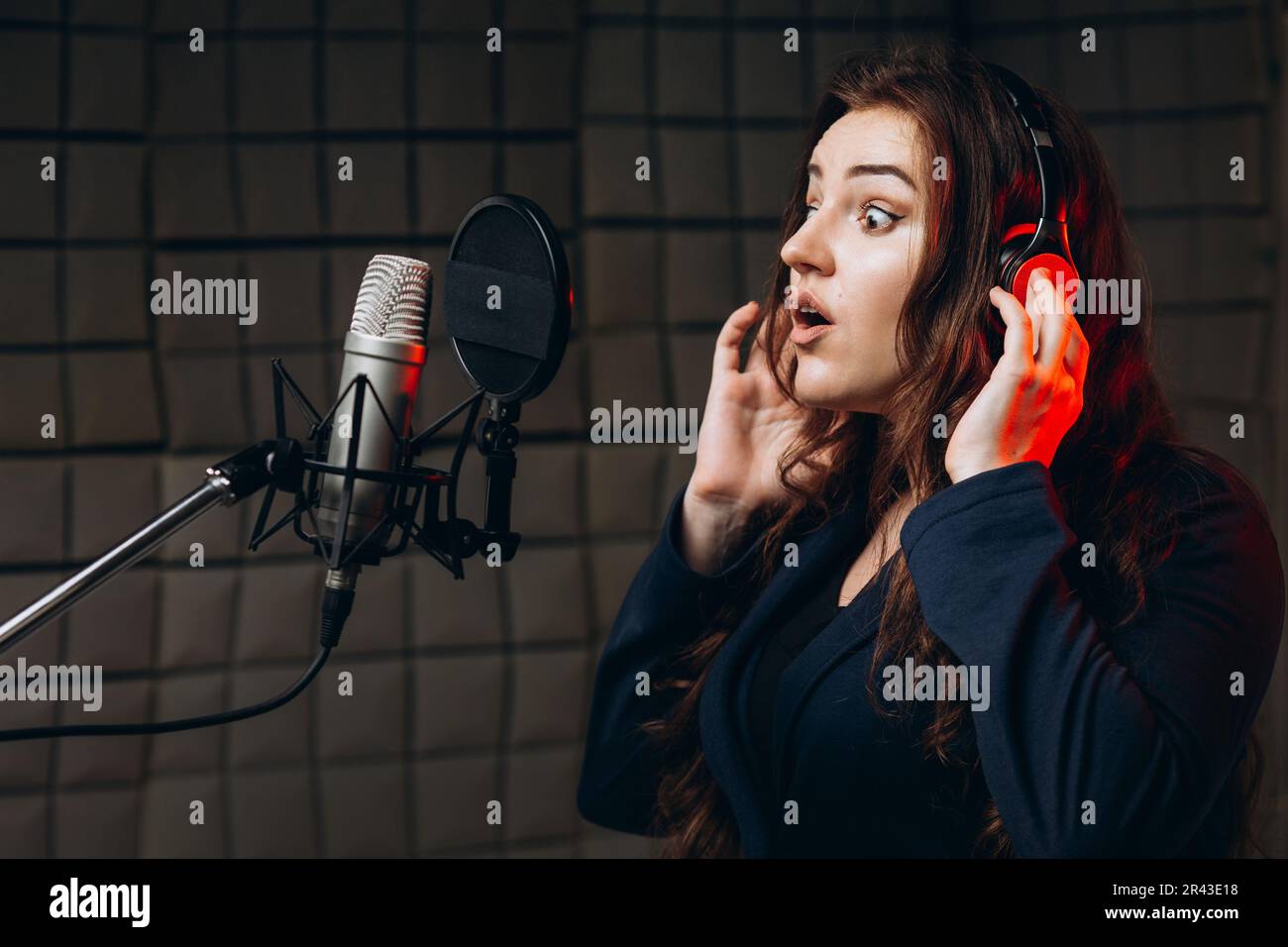 Female with microphone recording a voice for dubbing in music studio ...