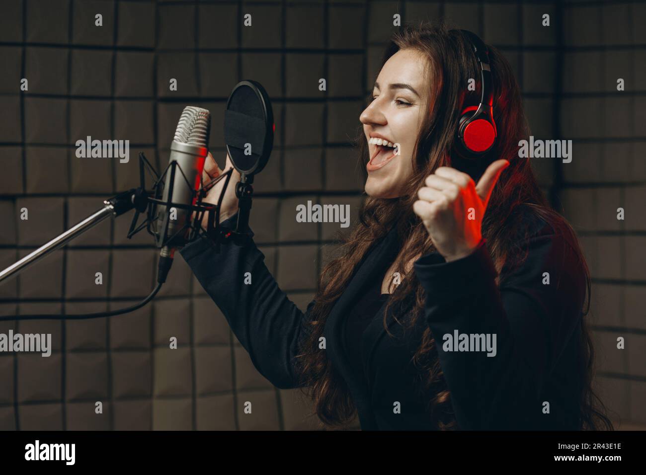 Female with microphone recording a voice for dubbing in music studio ...
