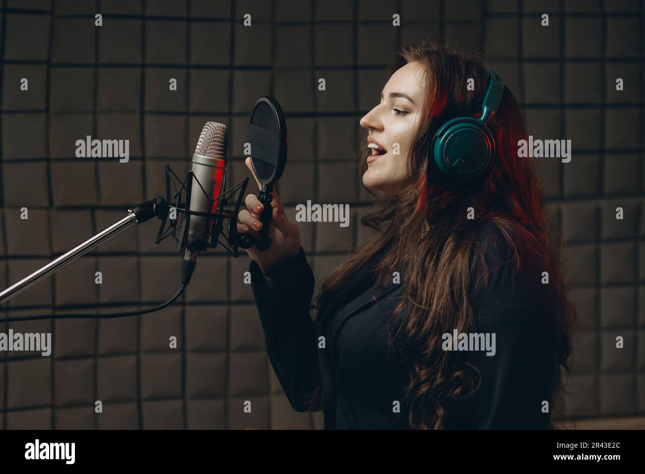 Female with microphone recording a voice for dubbing in music studio ...