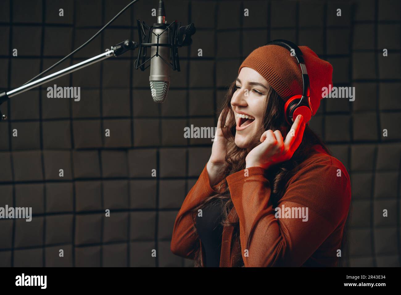 Young woman in headphones emotionally singing in microphone in the ...