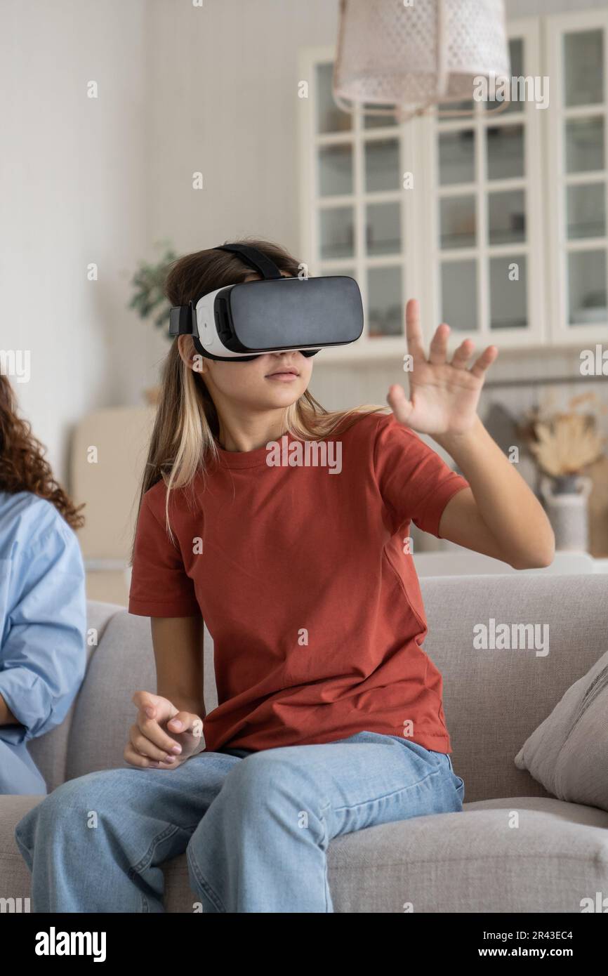 Curious teen girl in virtual reality glasses stretches hand forward use ...