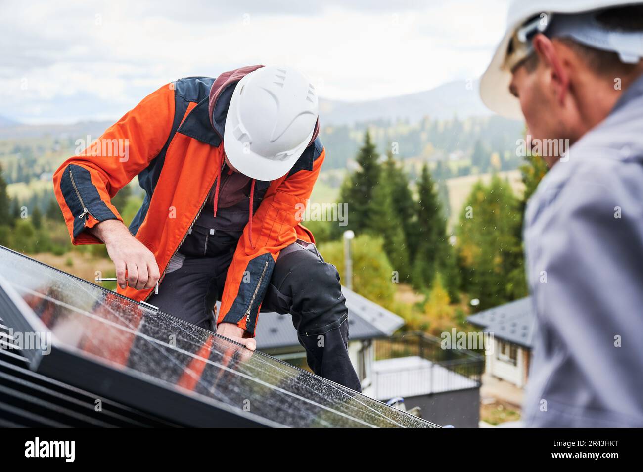 Roofers installing photovoltaic solar panels on roof of house. Men ...
