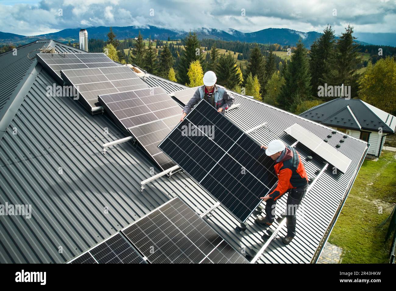 Workers installing solar panels on a roof of house. Solar battery ...
